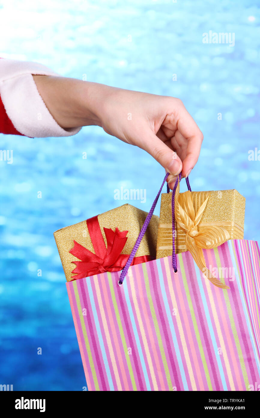 Hand holds package with New Year gifts on blue background Stock Photo ...