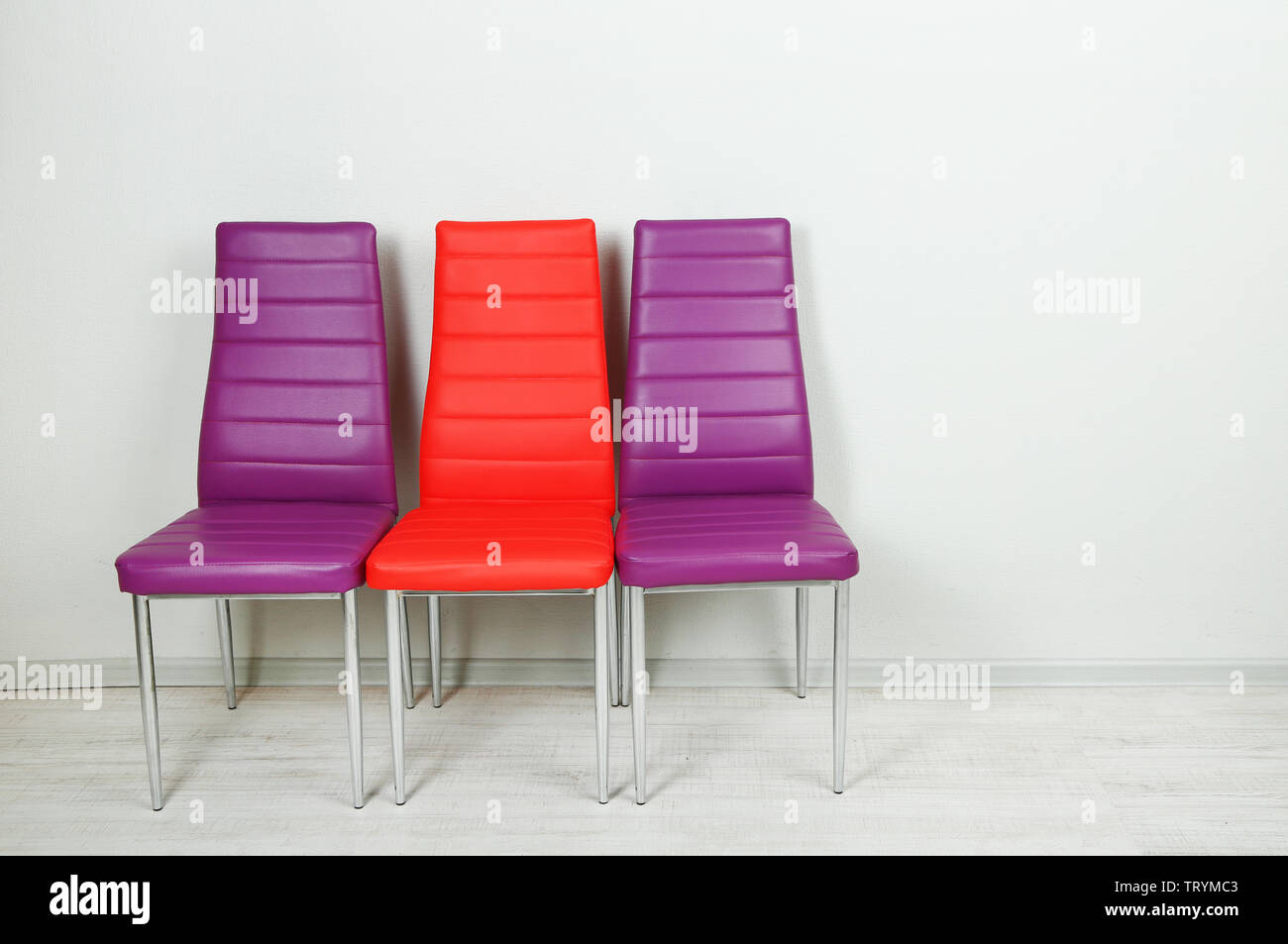 Modern color chairs on wall background Stock Photo - Alamy