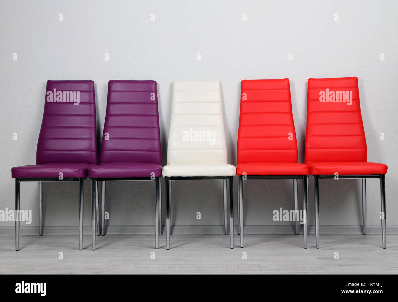 Modern color chairs on wall background Stock Photo - Alamy