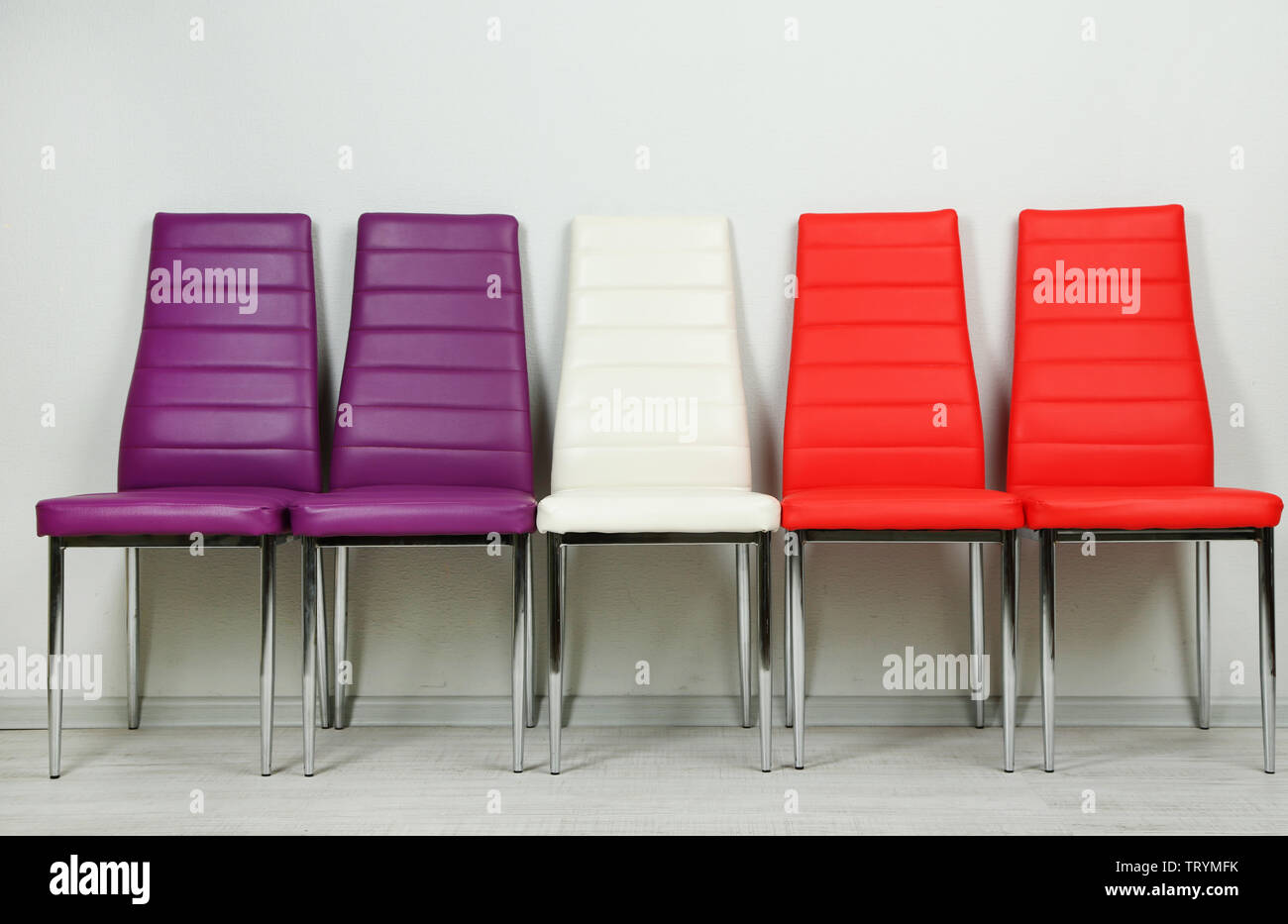 Modern color chairs on wall background Stock Photo - Alamy