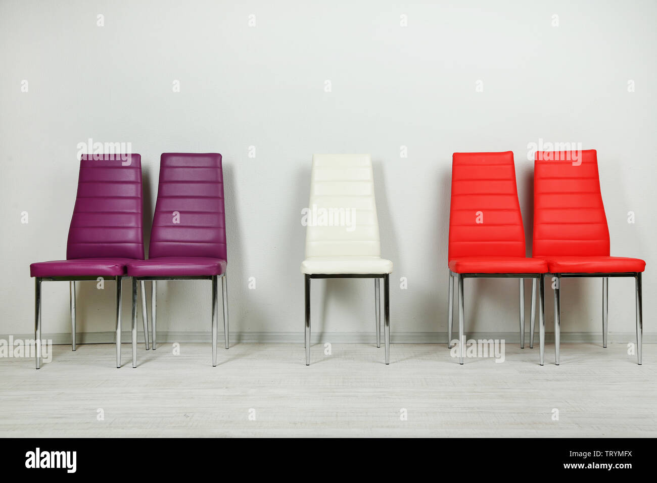 Modern color chairs on wall background Stock Photo - Alamy
