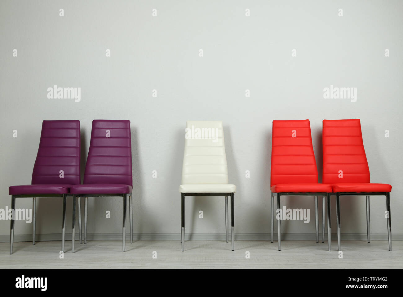 Modern color chairs on wall background Stock Photo - Alamy