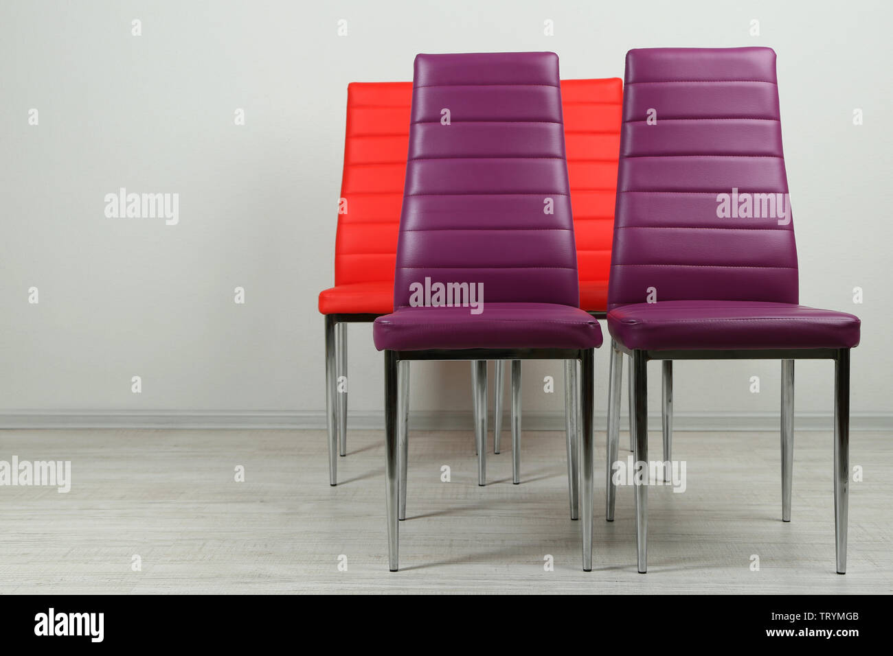 Modern color chairs on wall background Stock Photo - Alamy