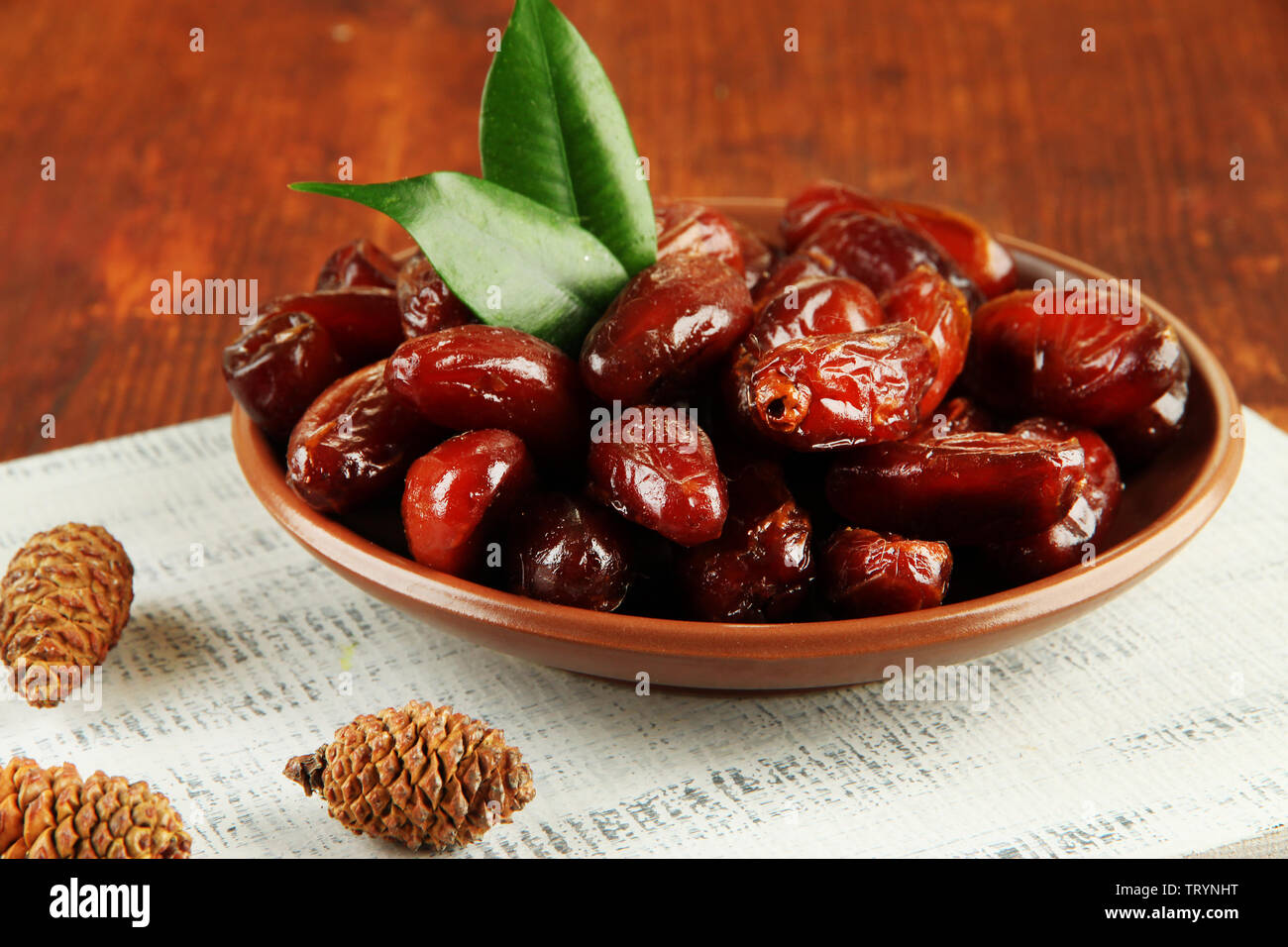 Dried dates on plate with bumps on wooden background Stock Photo - Alamy