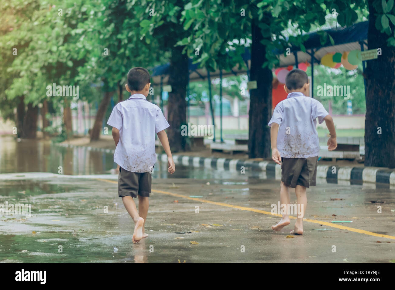 Boy students leave the classroom to walk on the street after heavy rain ...