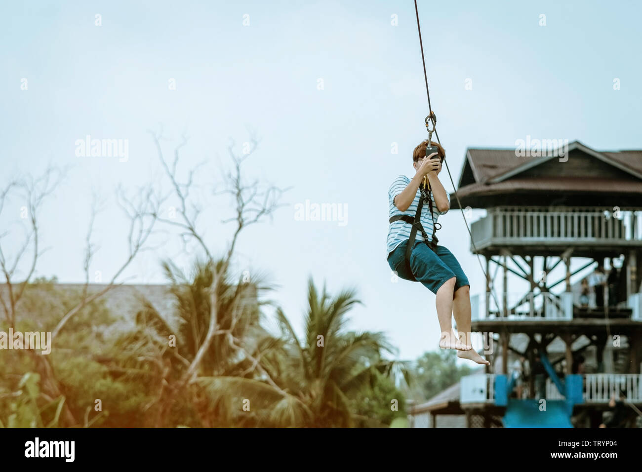 A male tourist flying on a zipline aka flying fox across the lake at ...