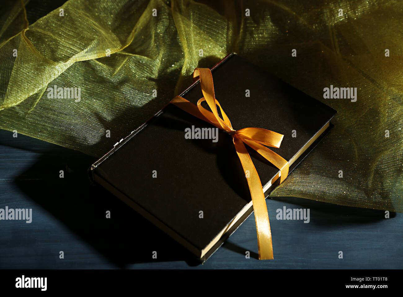 Book wrapped with color ribbon, on wooden background Stock Photo - Alamy
