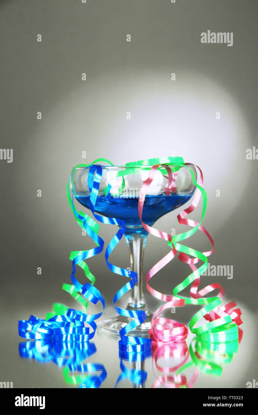 Glass of cocktail and streamer after party on gray background Stock ...
