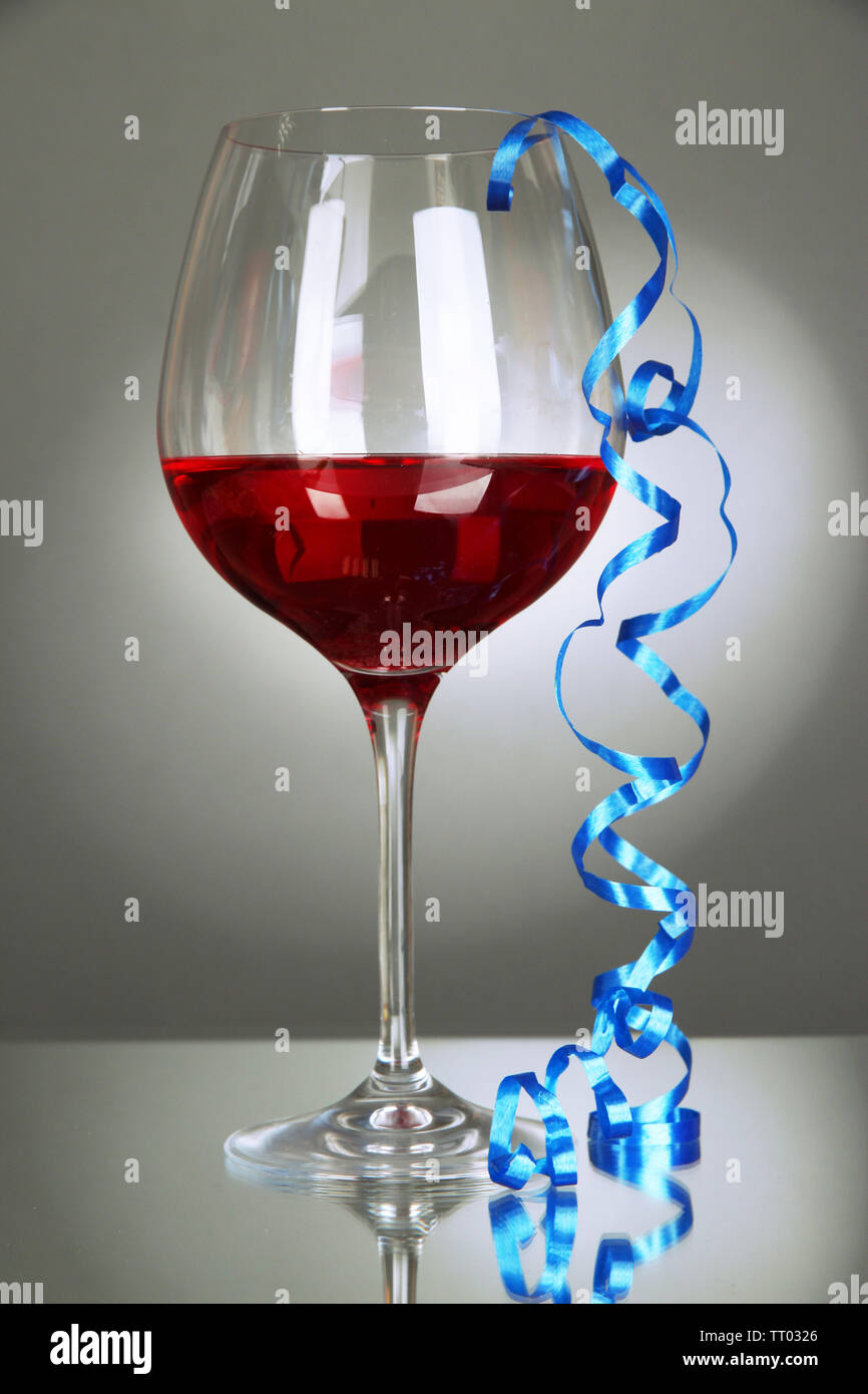 Glass of red wine and streamer after party on gray background Stock ...