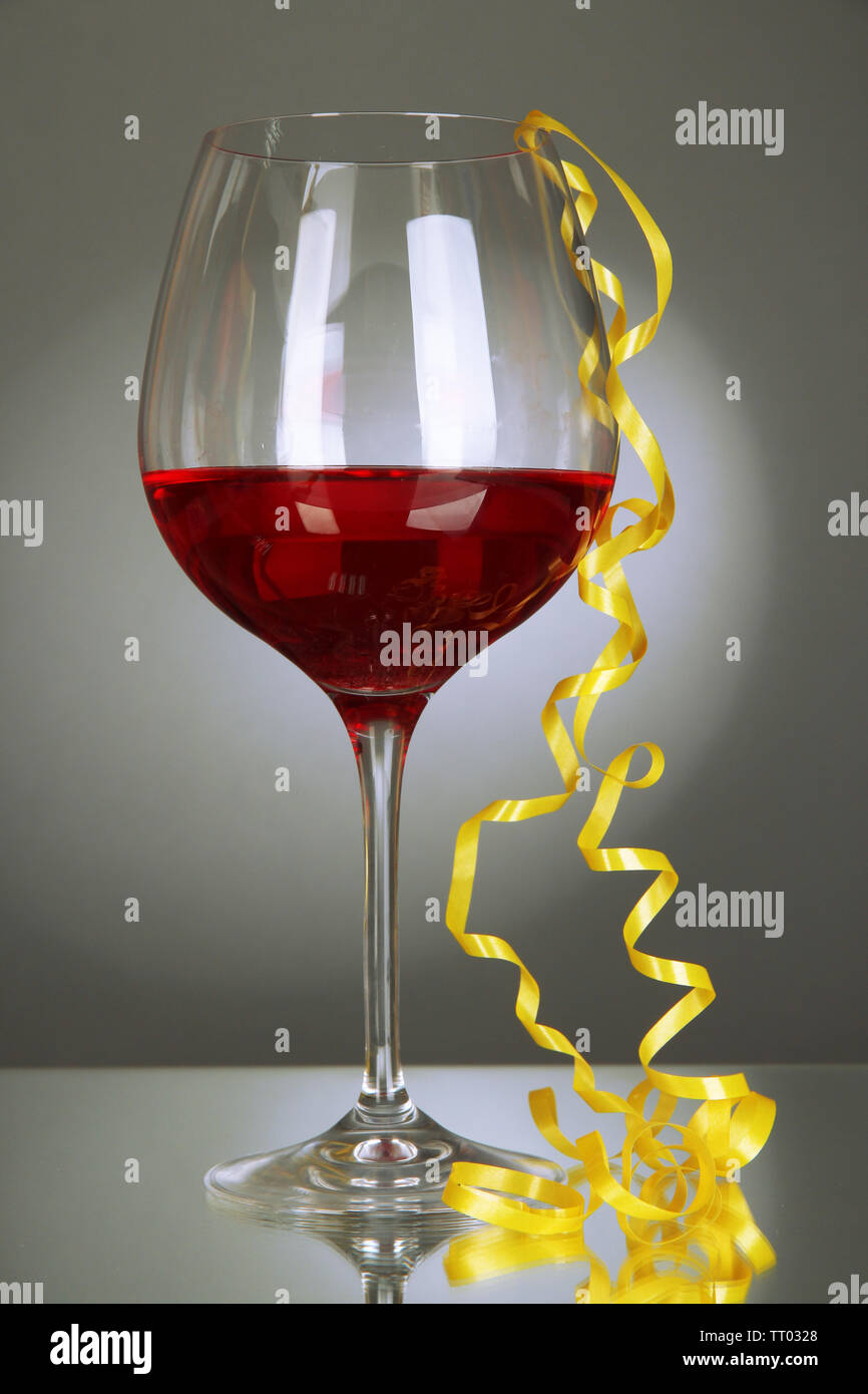 Glass of red wine and streamer after party on gray background Stock ...