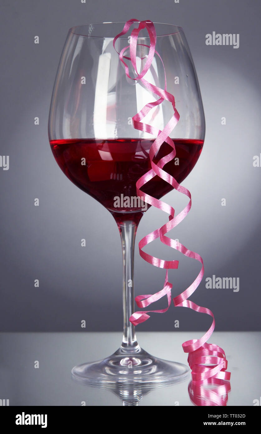 Glass of red wine and streamer after party on gray background Stock ...