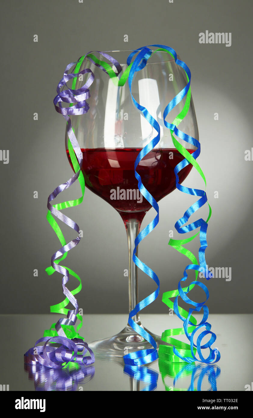 Glass of red wine and streamer after party on gray background Stock ...