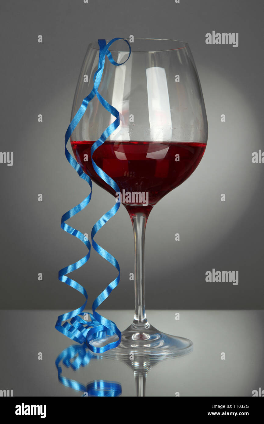Glass of red wine and streamer after party on gray background Stock ...