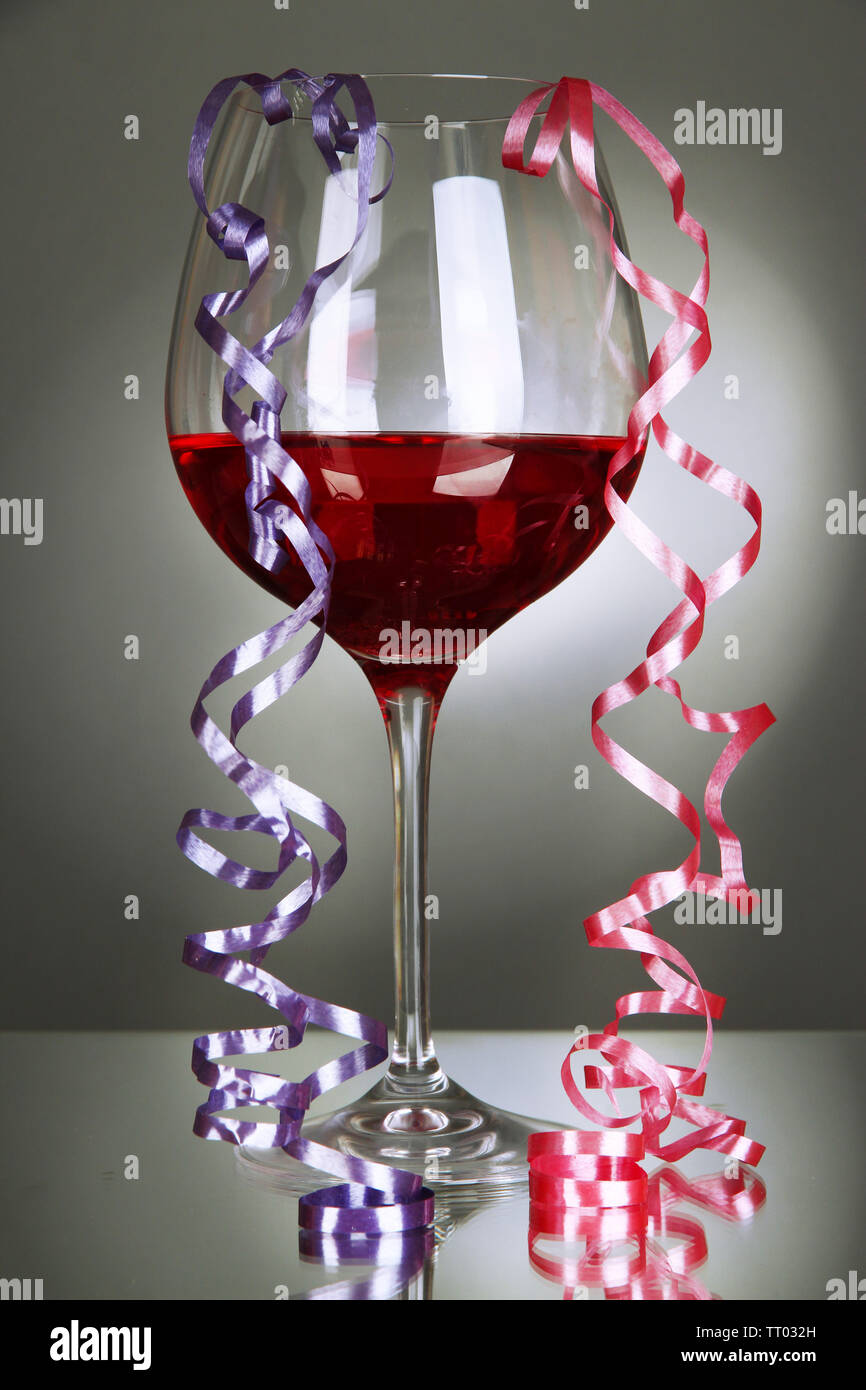 Glass of red wine and streamer after party on gray background Stock ...