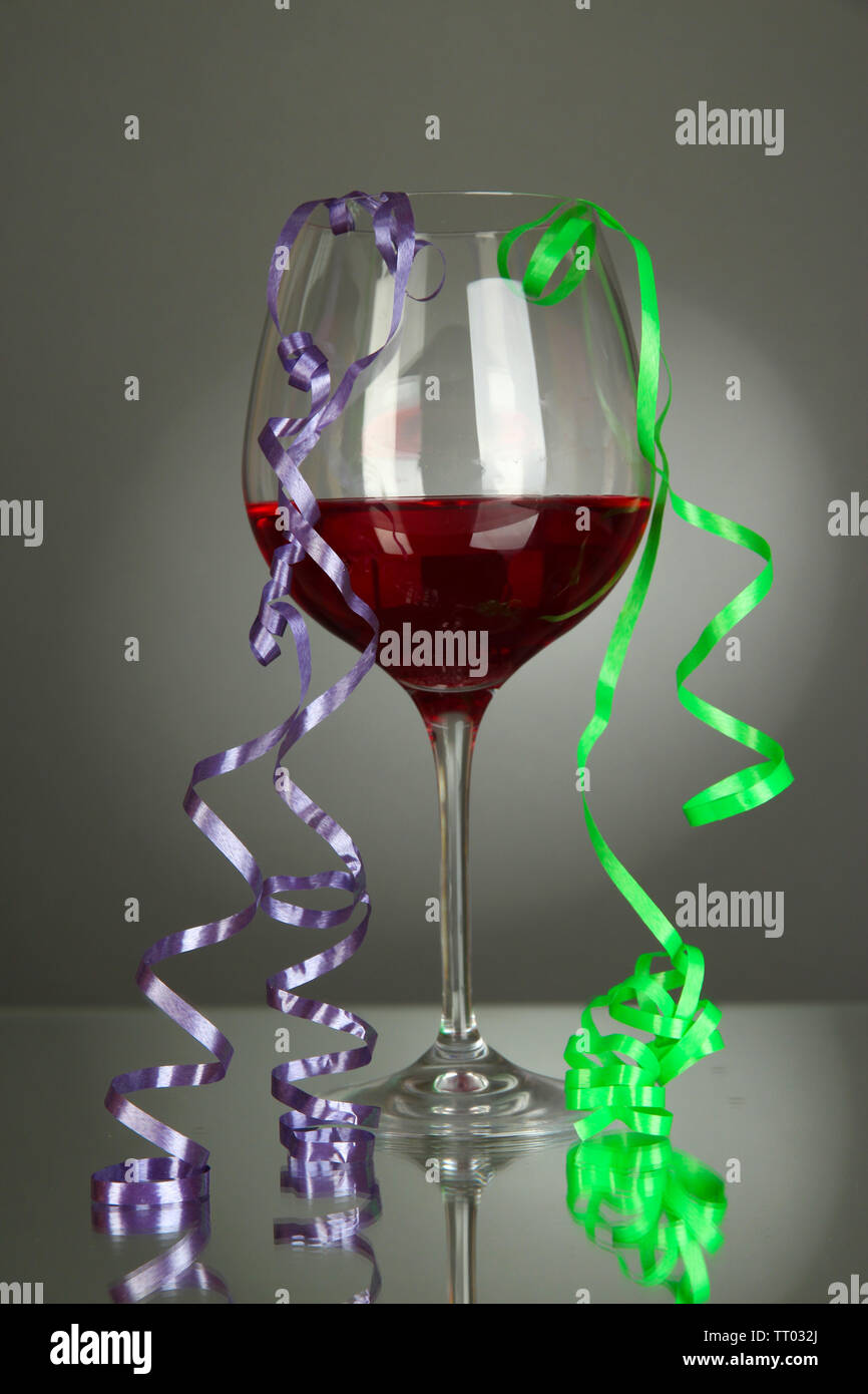 Glass of red wine and streamer after party on gray background Stock ...