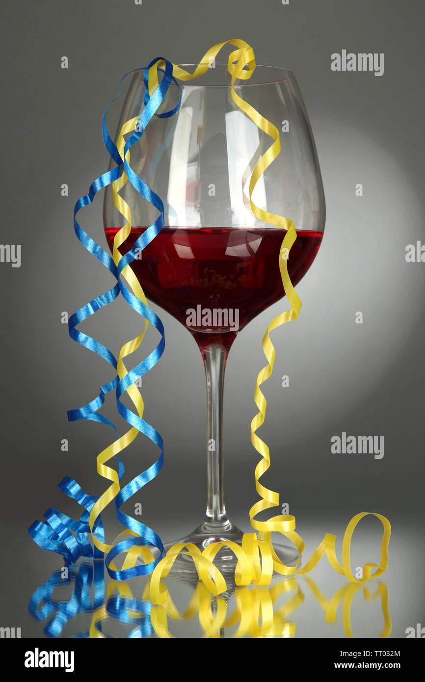 Glass of red wine and streamer after party on gray background Stock ...