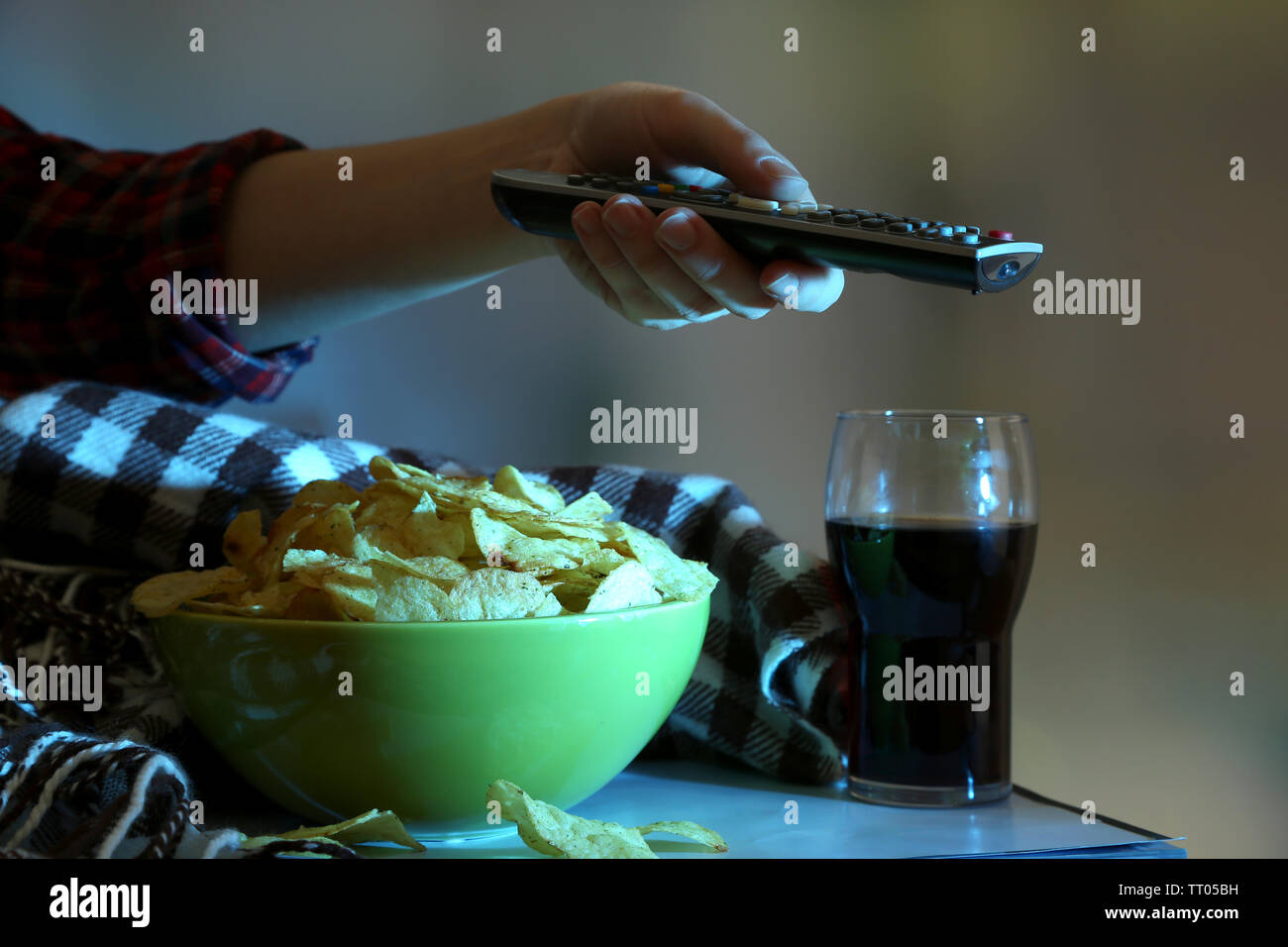 Someone watching TV with crisps and cola in room Stock Photo - Alamy