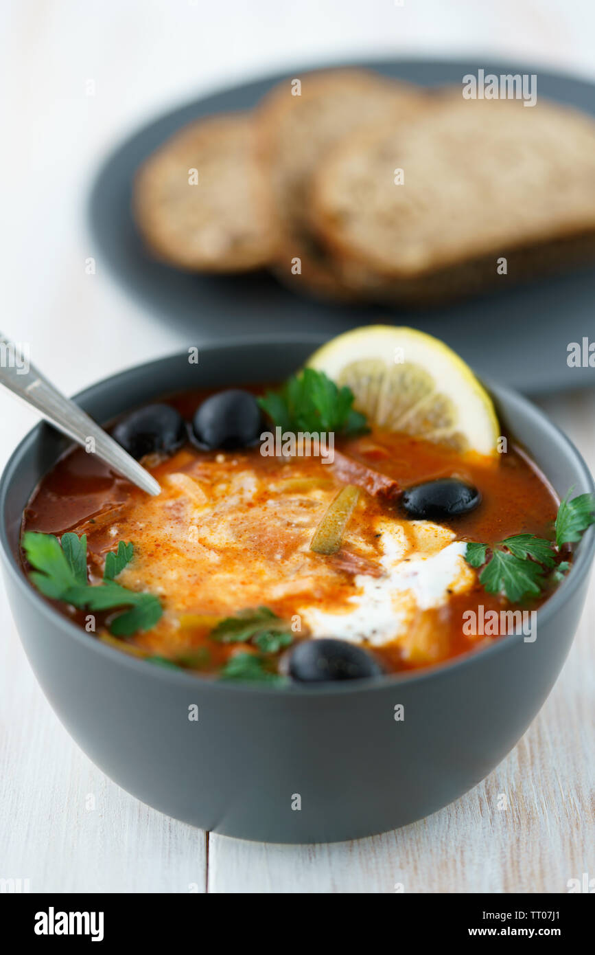 Meat solyanka served with rye bread in a grey ceramic bowl. White ...