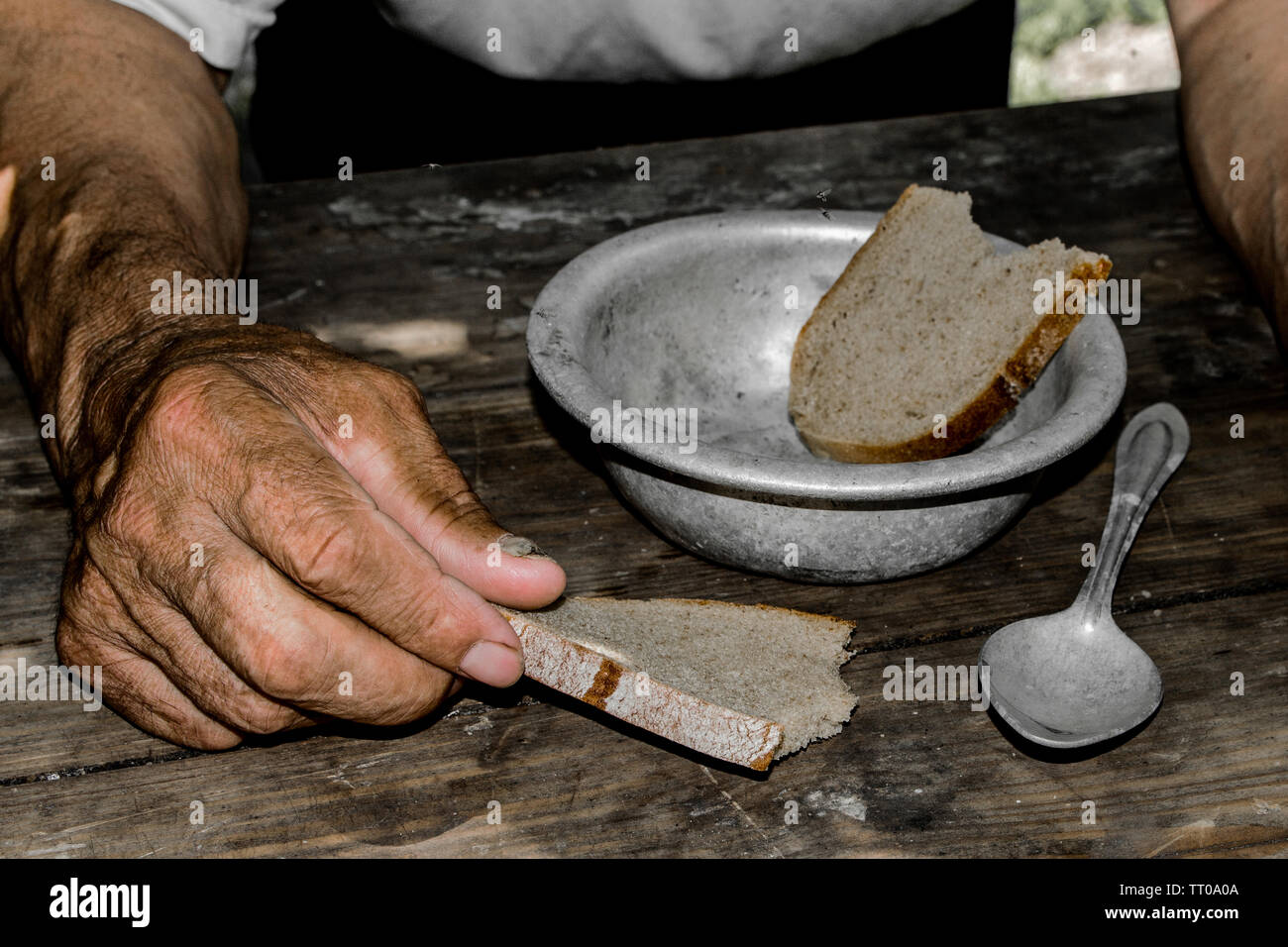 Hands the poor old man's, piece of bread and empty bowl on wood ...