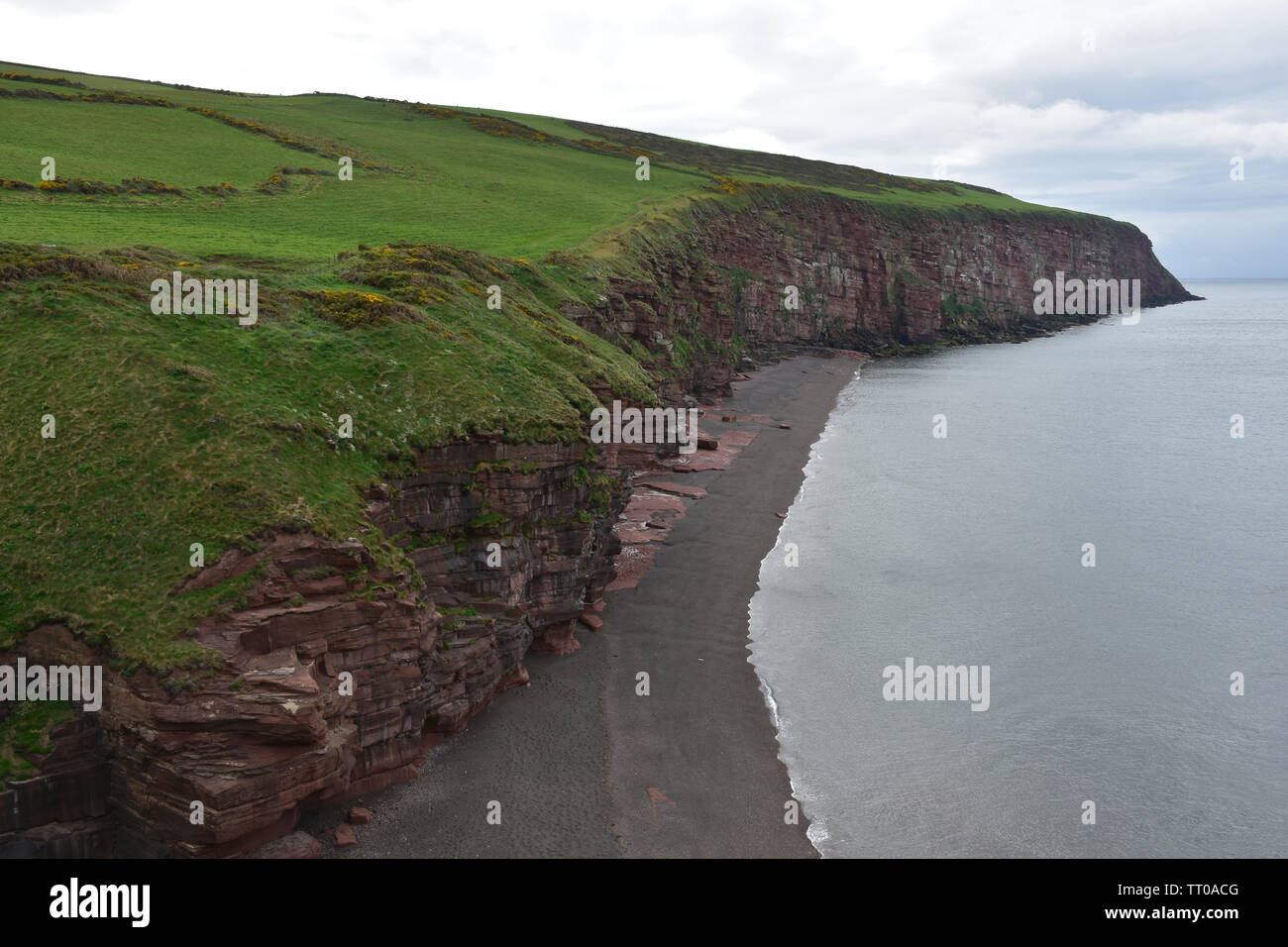Irish Sea with red rock sea cliffs along a beach in West Cumbria Stock ...