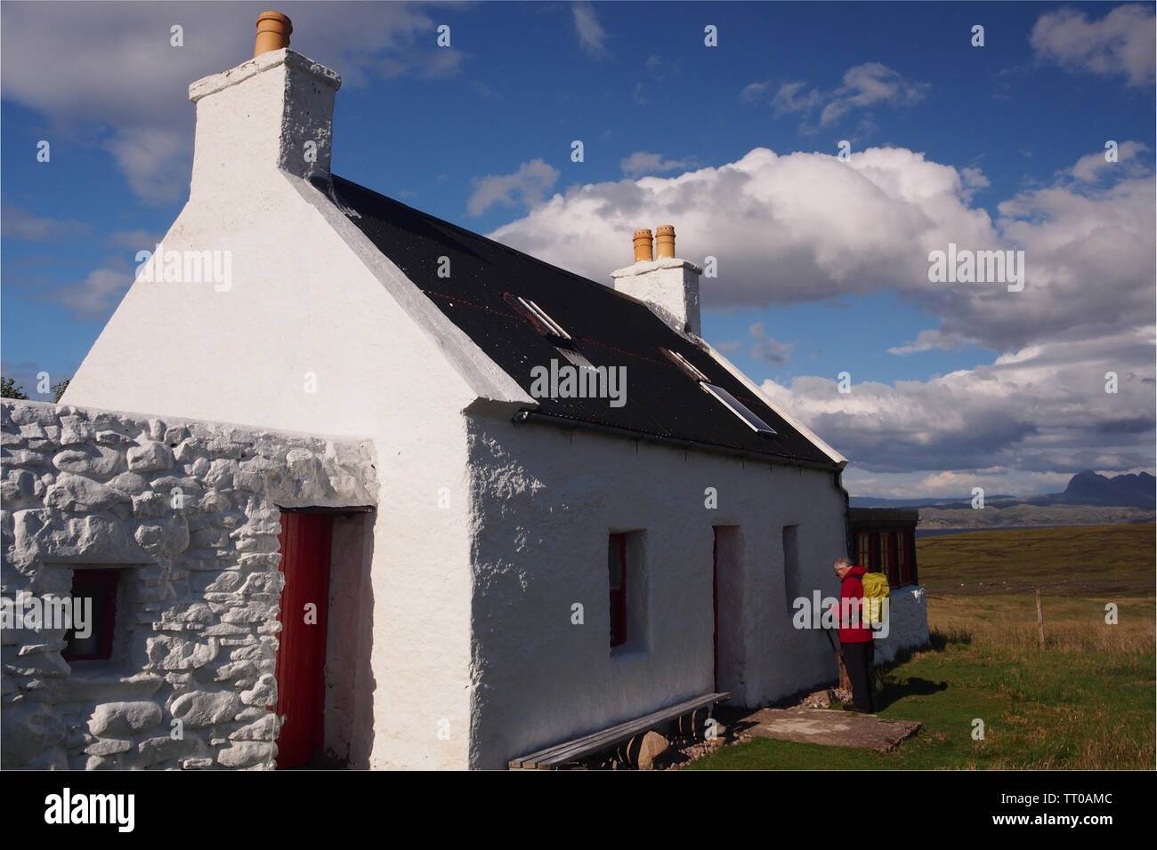 A backpacker looking at a crofter's cottage on the Coigach Peninsula ...