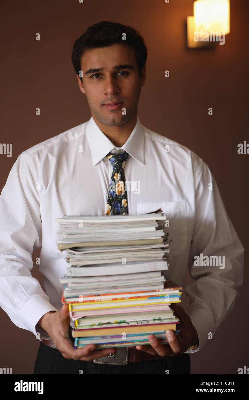 Businessman carrying stack of books Stock Photo - Alamy