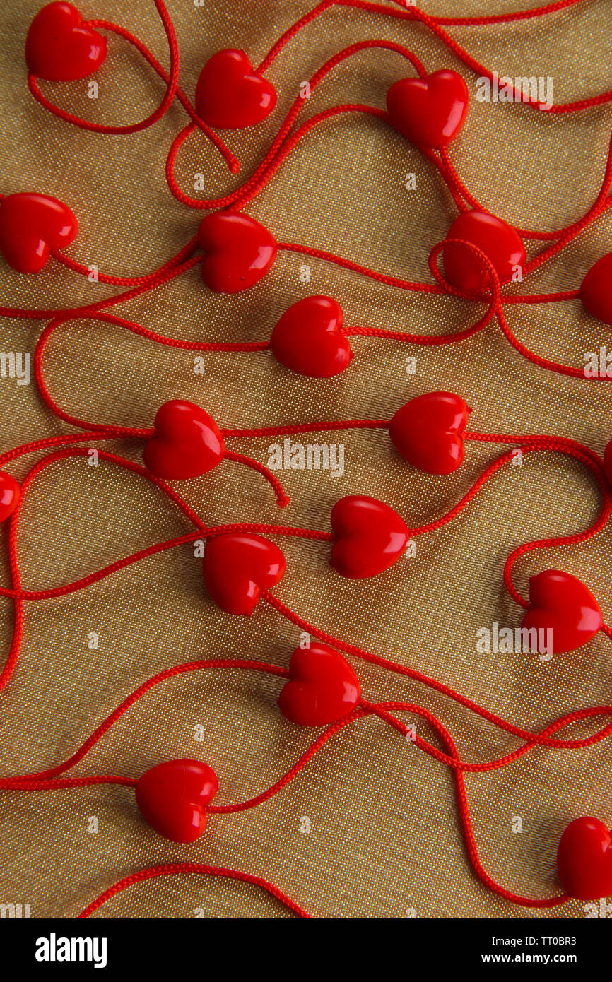 Heart-shaped beads on string on fabric background Stock Photo - Alamy