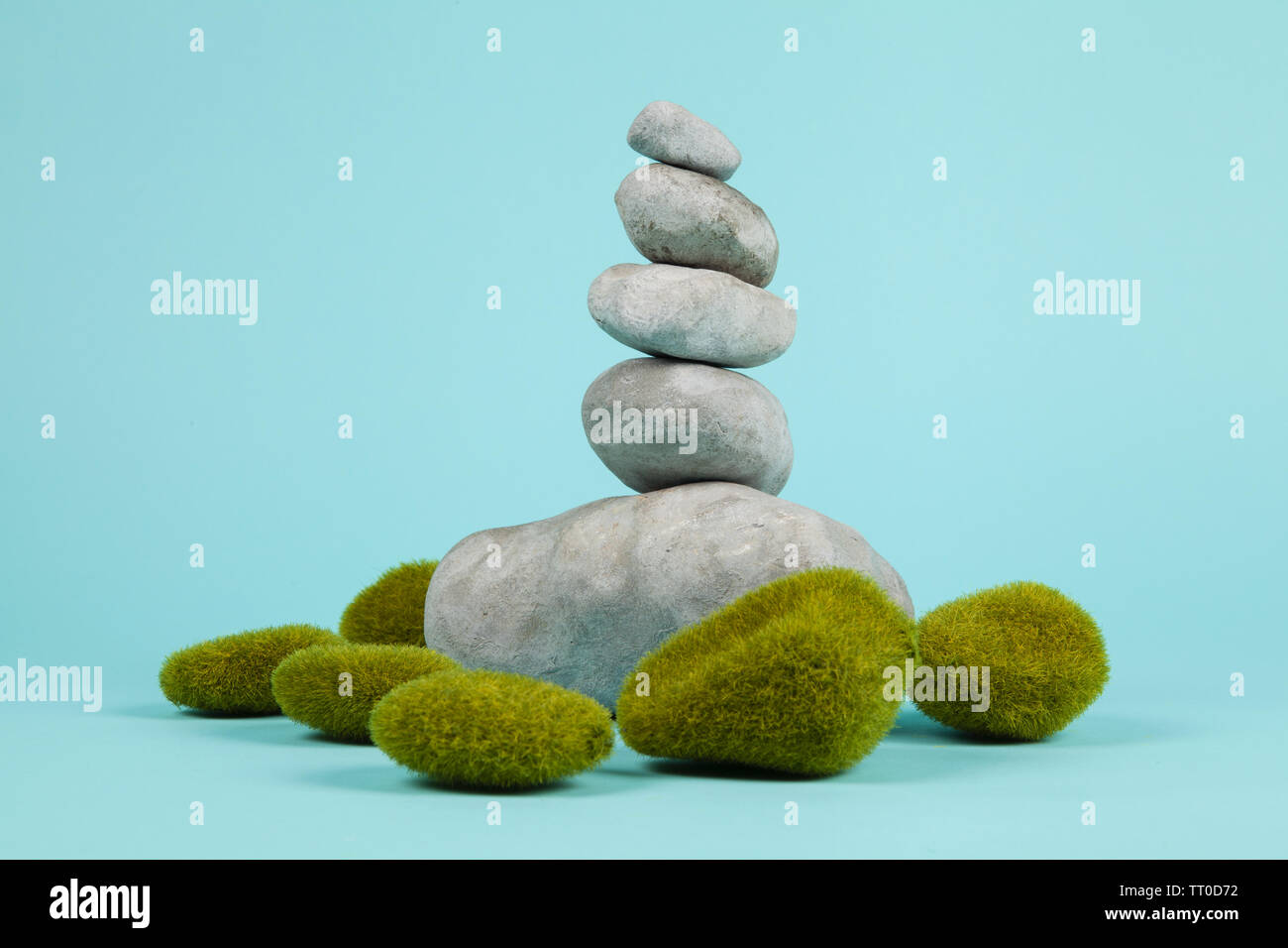 a pile of Zen stones in balance surrounded by moss rocks on a turquoise ...