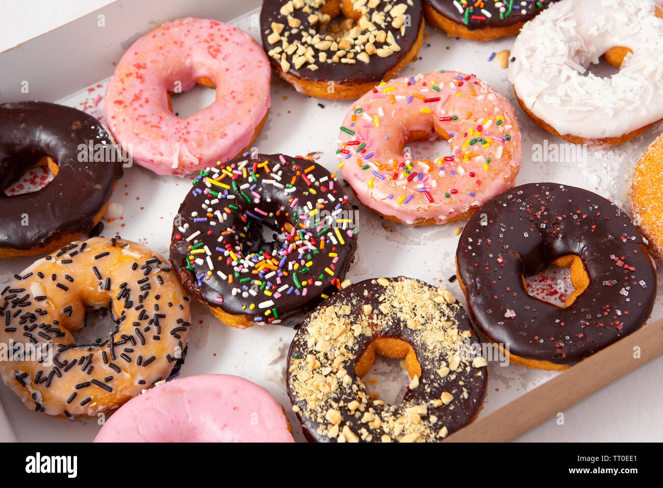 Box of mixed freshly baked doughnuts with toppings in a cardboard box ...