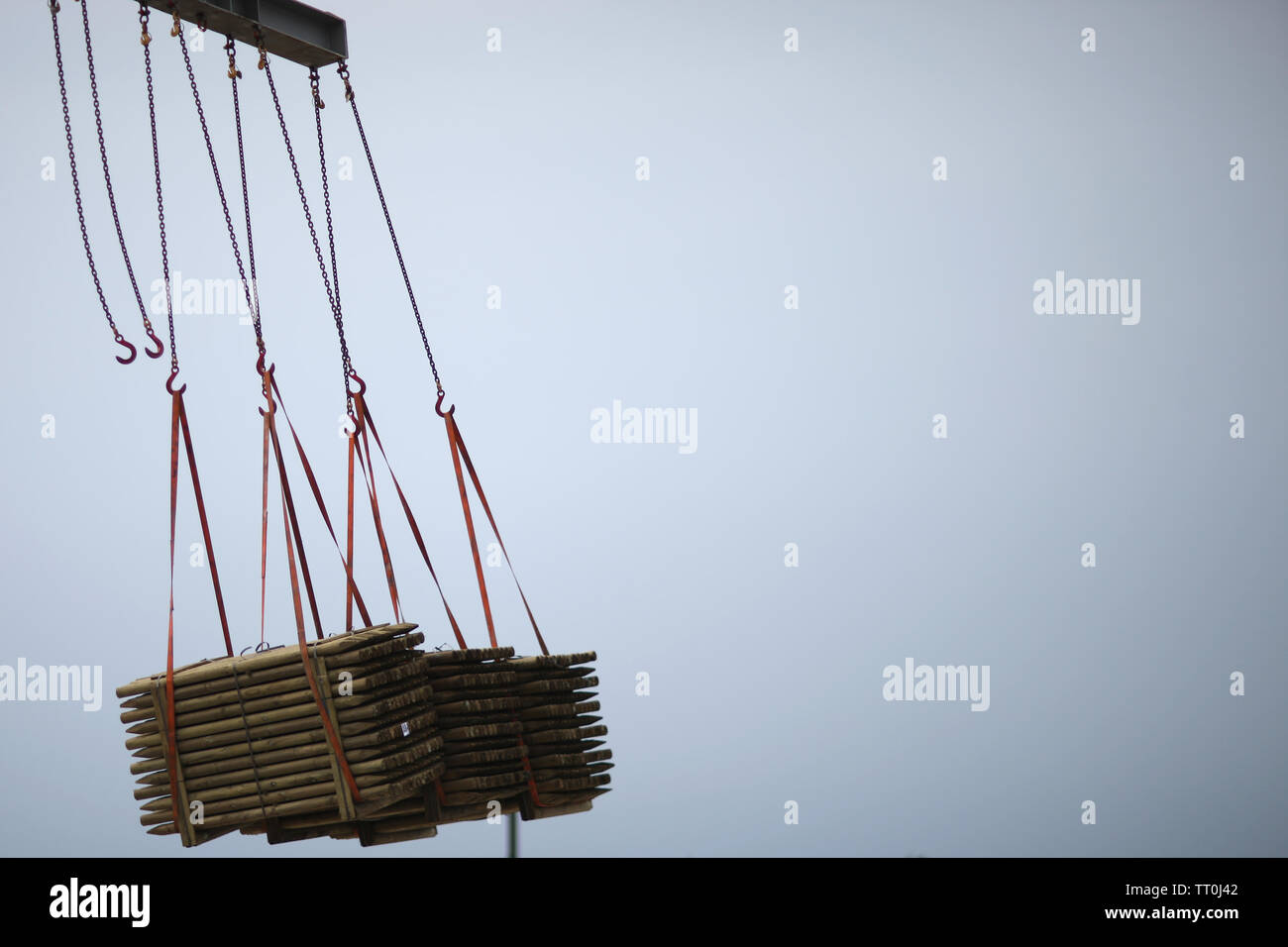 Three wooden products package pallet lifted by crane for loading onto a ...