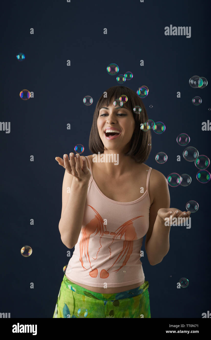 Indian young woman trying to hold floating bubbles Stock Photo - Alamy