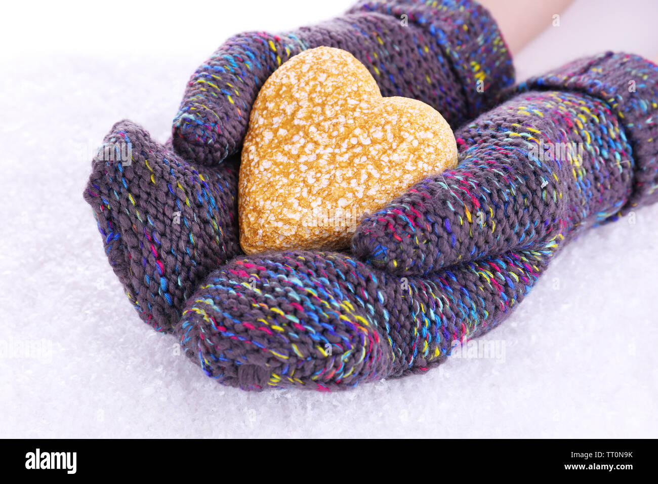 Female hands in mittens with heart on snow background Stock Photo - Alamy