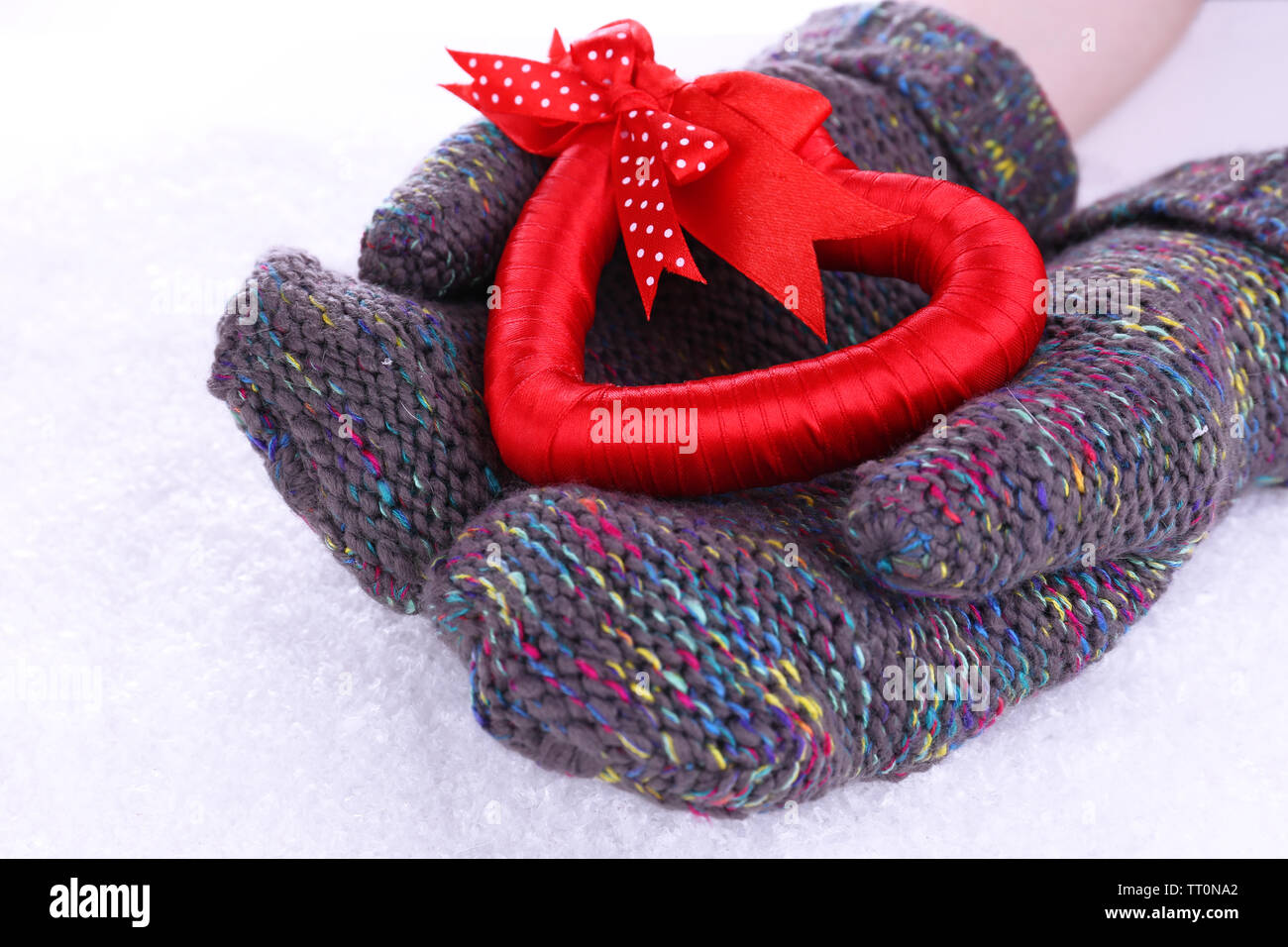 Female hands in mittens with heart on snow background Stock Photo - Alamy