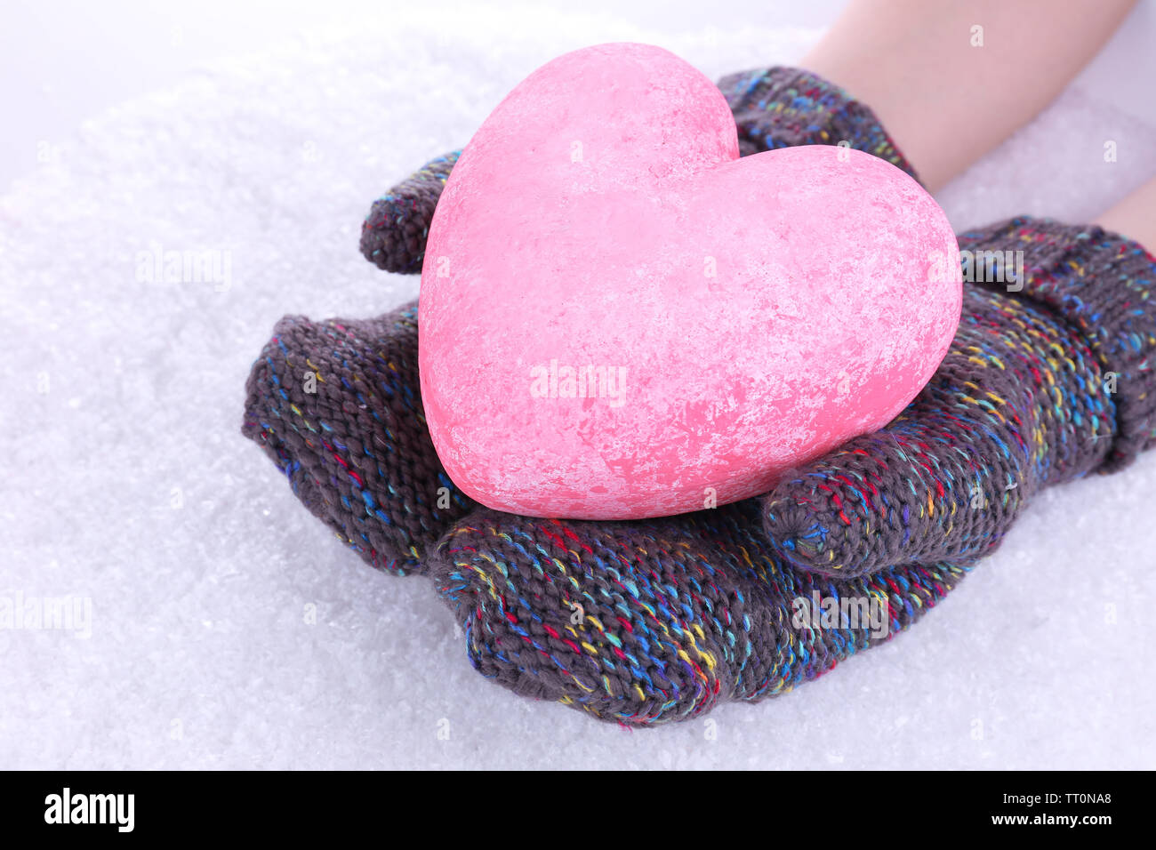 Female hands in mittens with heart on snow background Stock Photo - Alamy