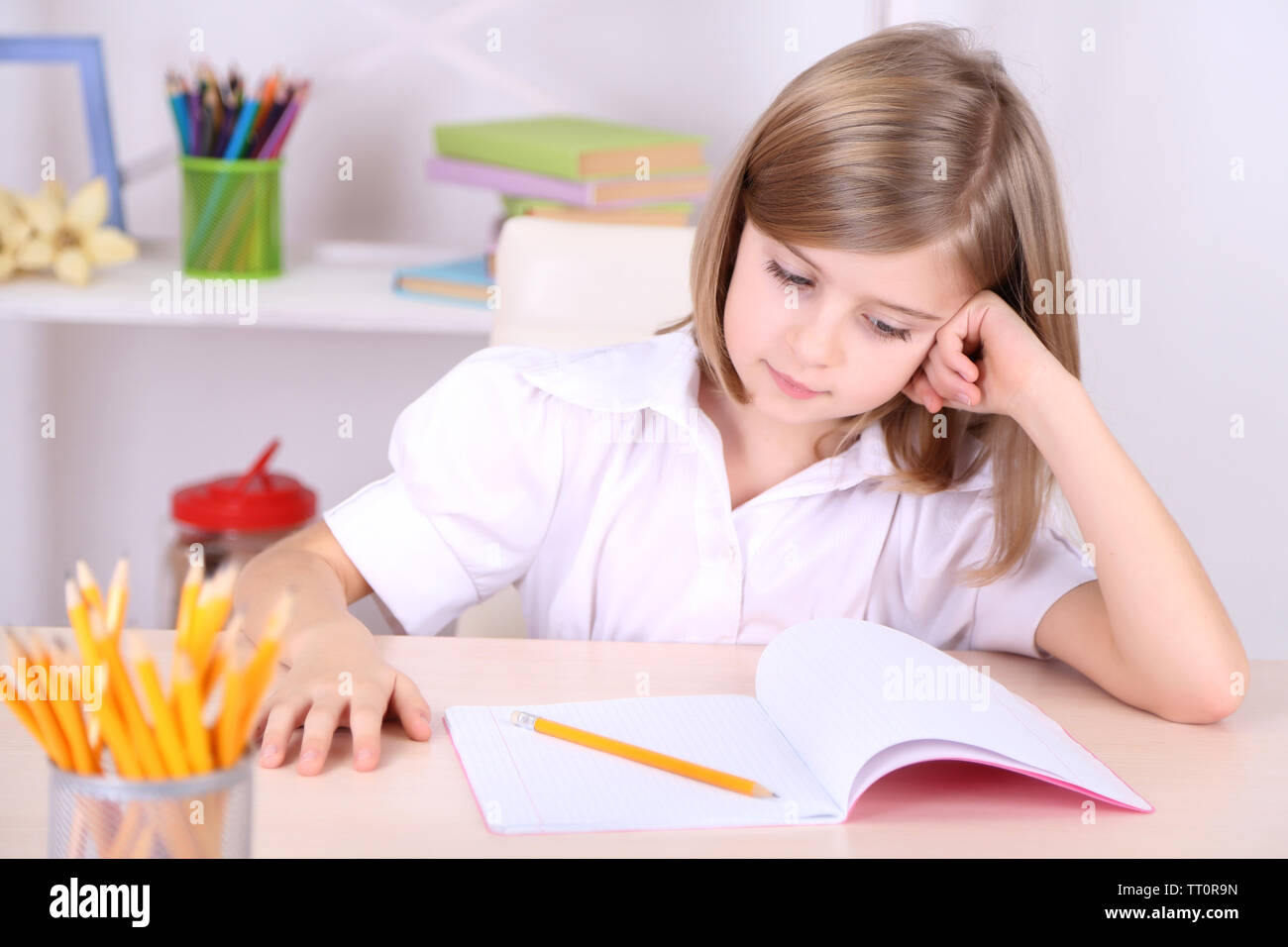 Little girl sitting at desk in room Stock Photo - Alamy