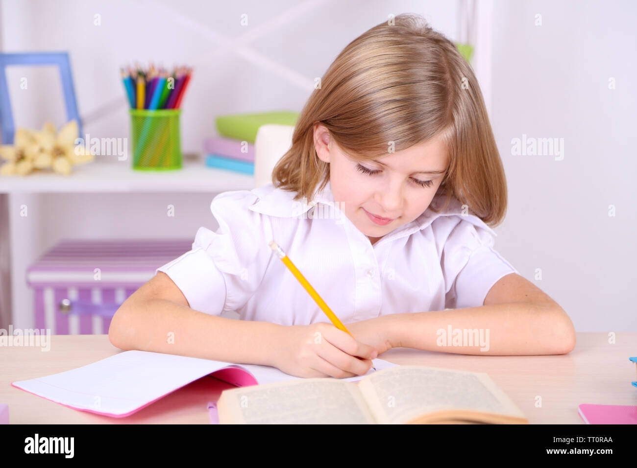 Little girl sitting at desk in room Stock Photo - Alamy