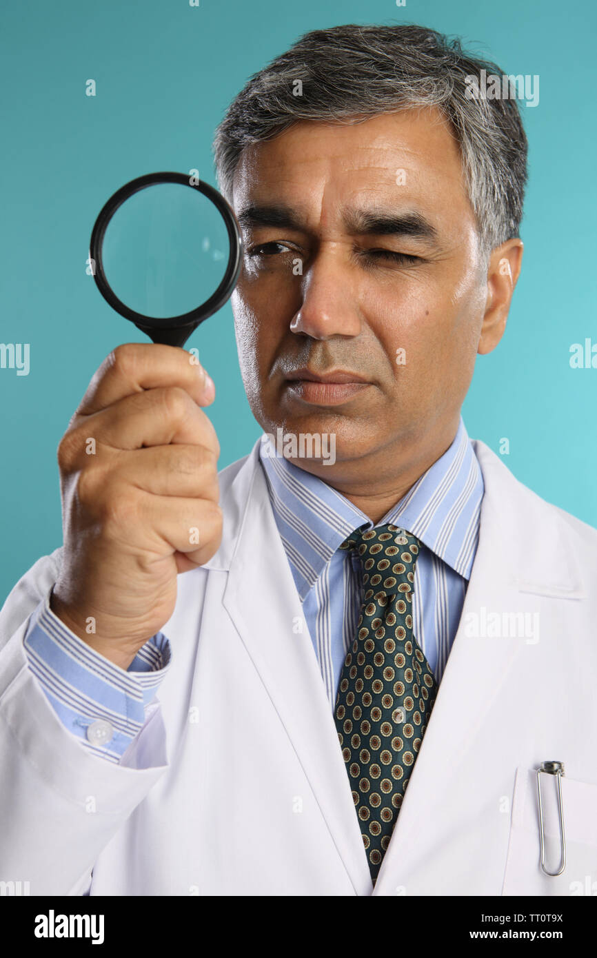 Male doctor looking through a magnifying glass Stock Photo - Alamy