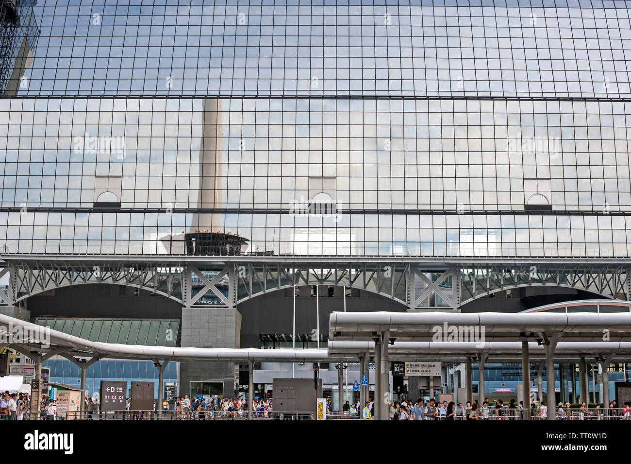 Passengers queuing for busses at the bus terminal beneath the glass ...