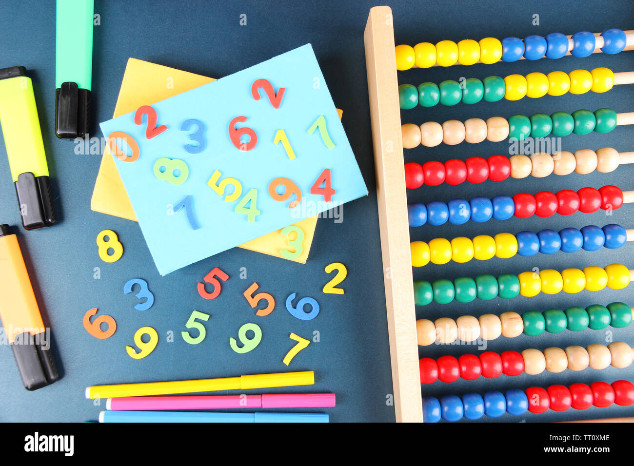 Colorful numbers, abacus, books and markers on school desk background ...