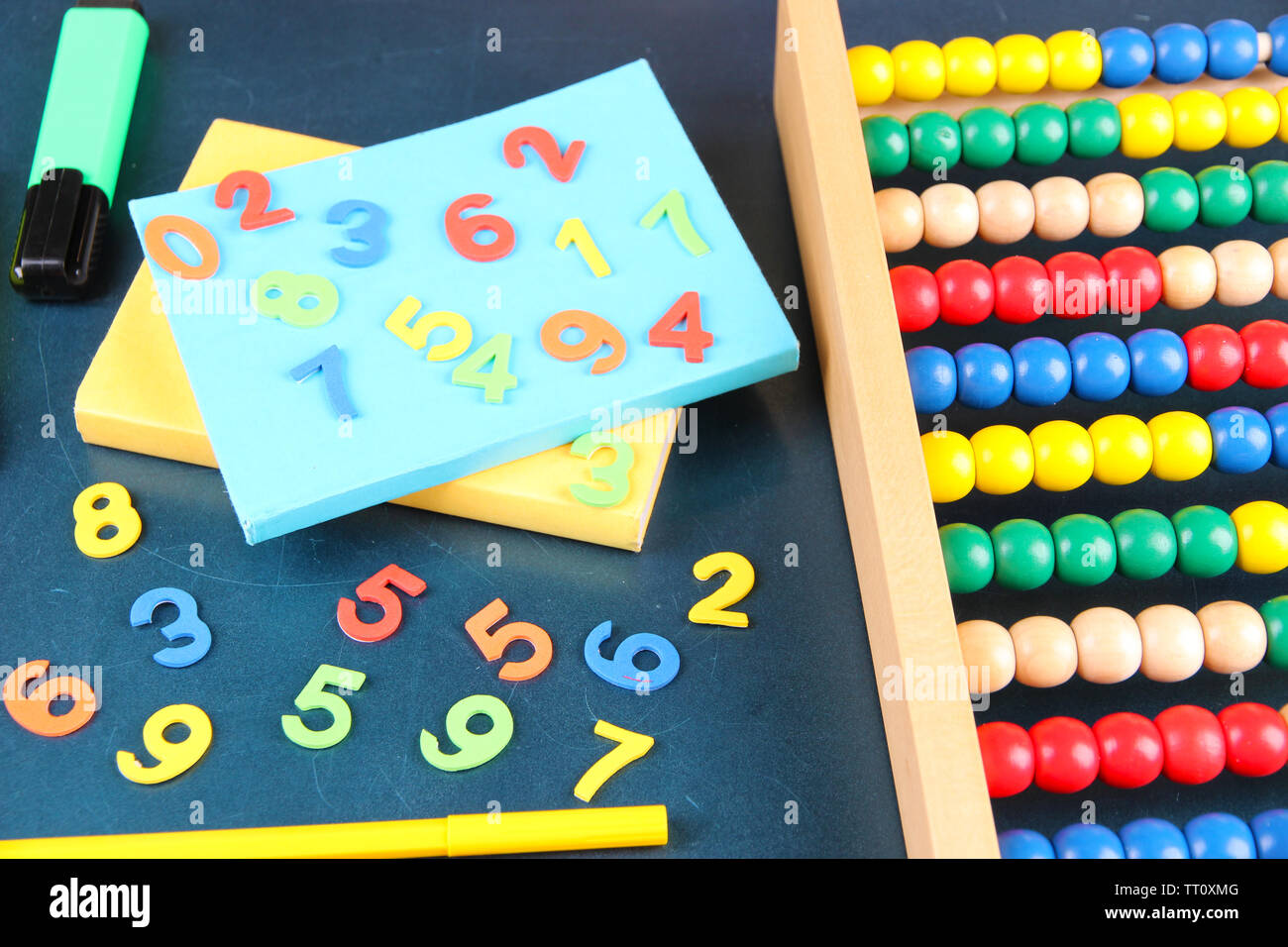 Colorful numbers, abacus, books and markers on school desk background ...