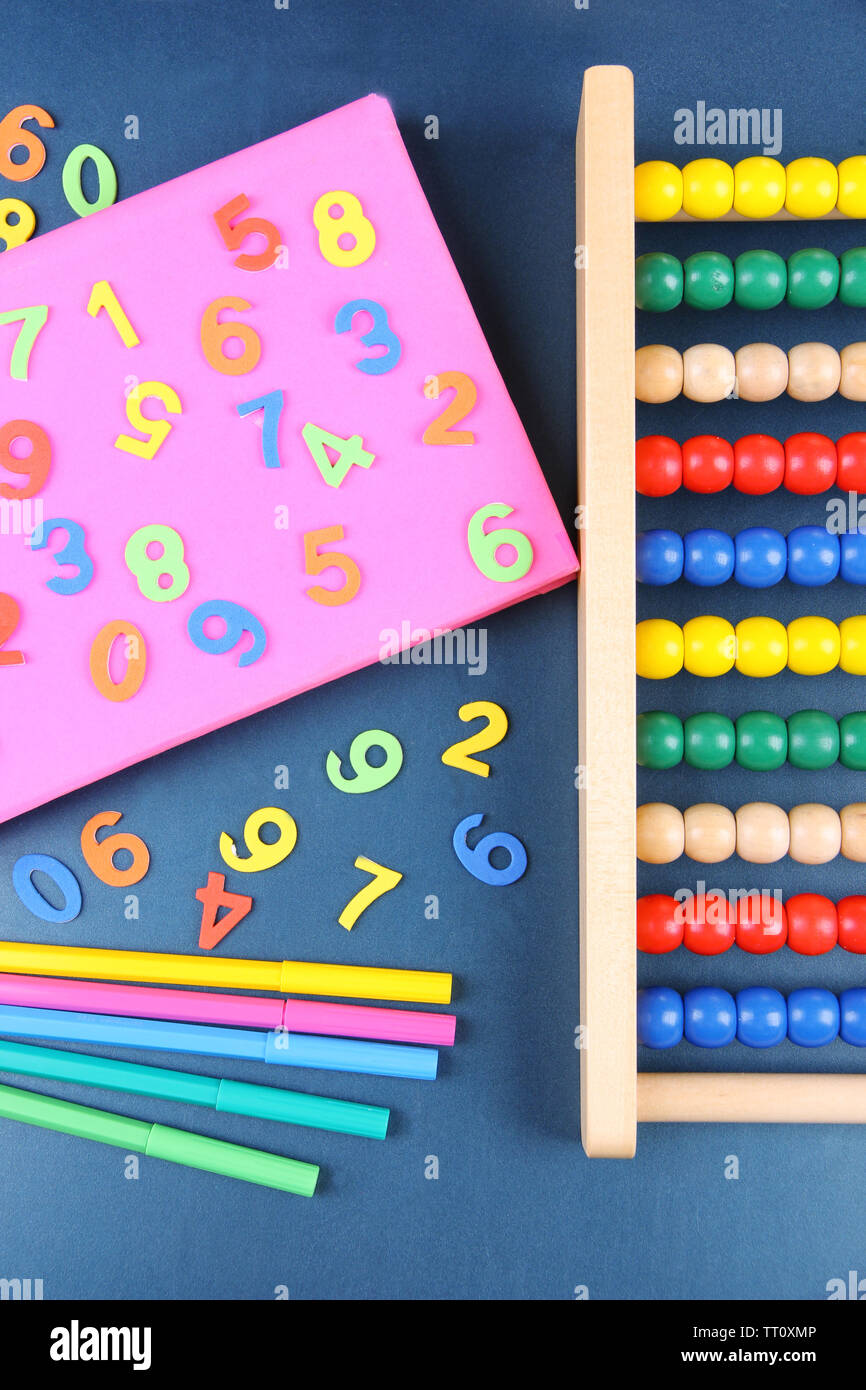 Colorful numbers, abacus, books and markers on school desk background ...