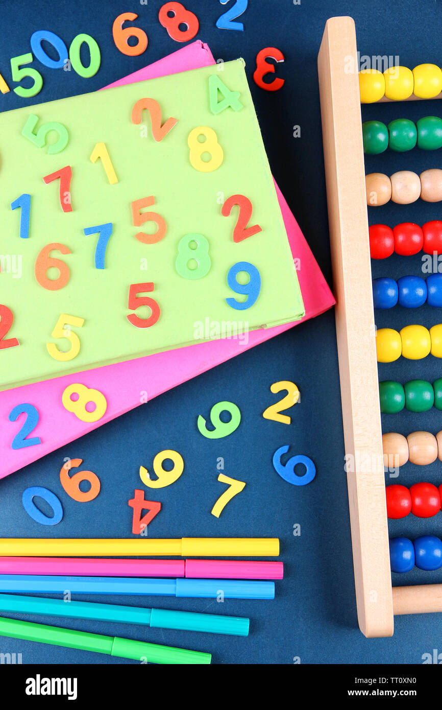 Colorful numbers, abacus, books and markers on school desk background ...