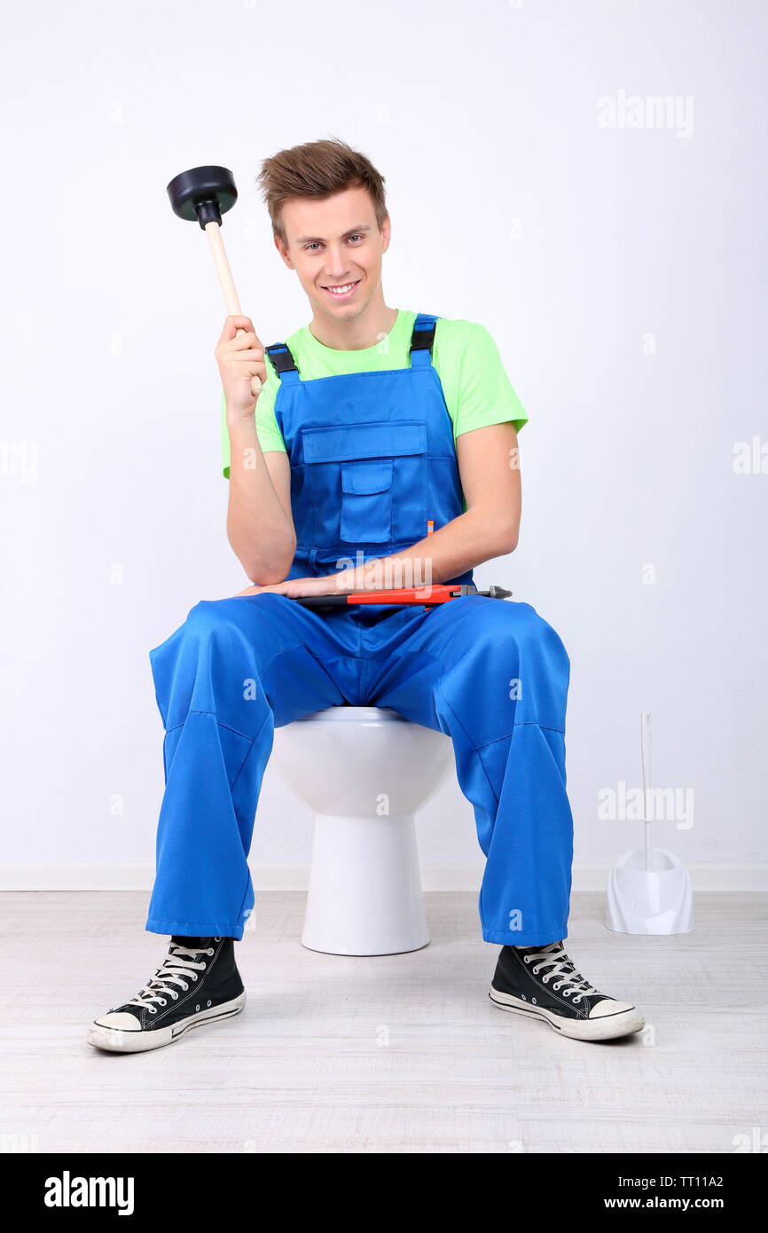 Plumber with toilet plunger on light background Stock Photo - Alamy