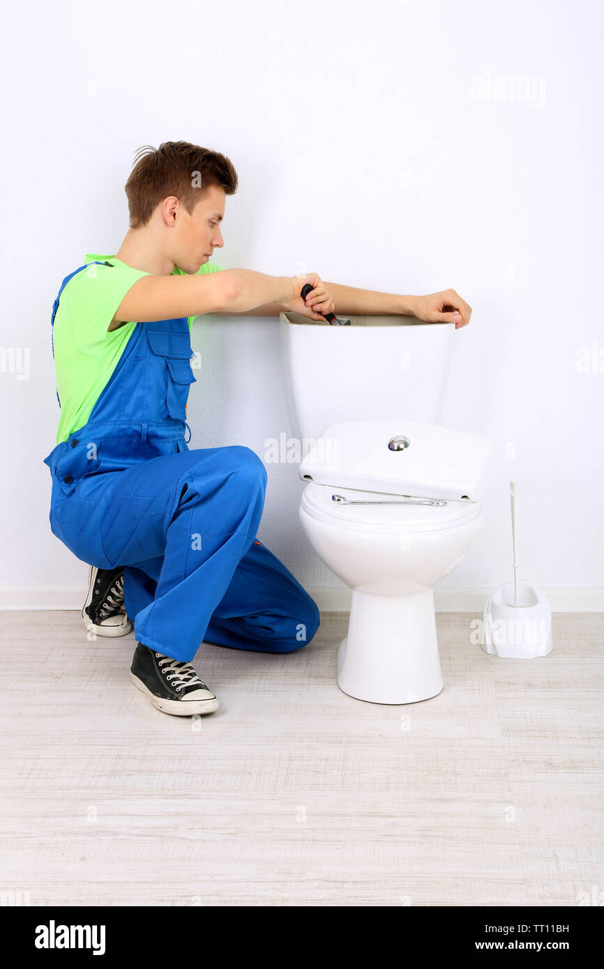 Plumber with toilet plunger on light background Stock Photo - Alamy