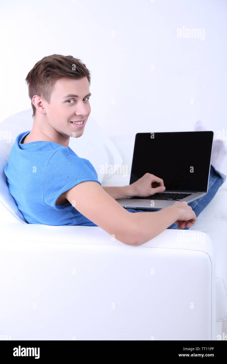 Guy sitting on sofa with laptop on white background Stock Photo - Alamy
