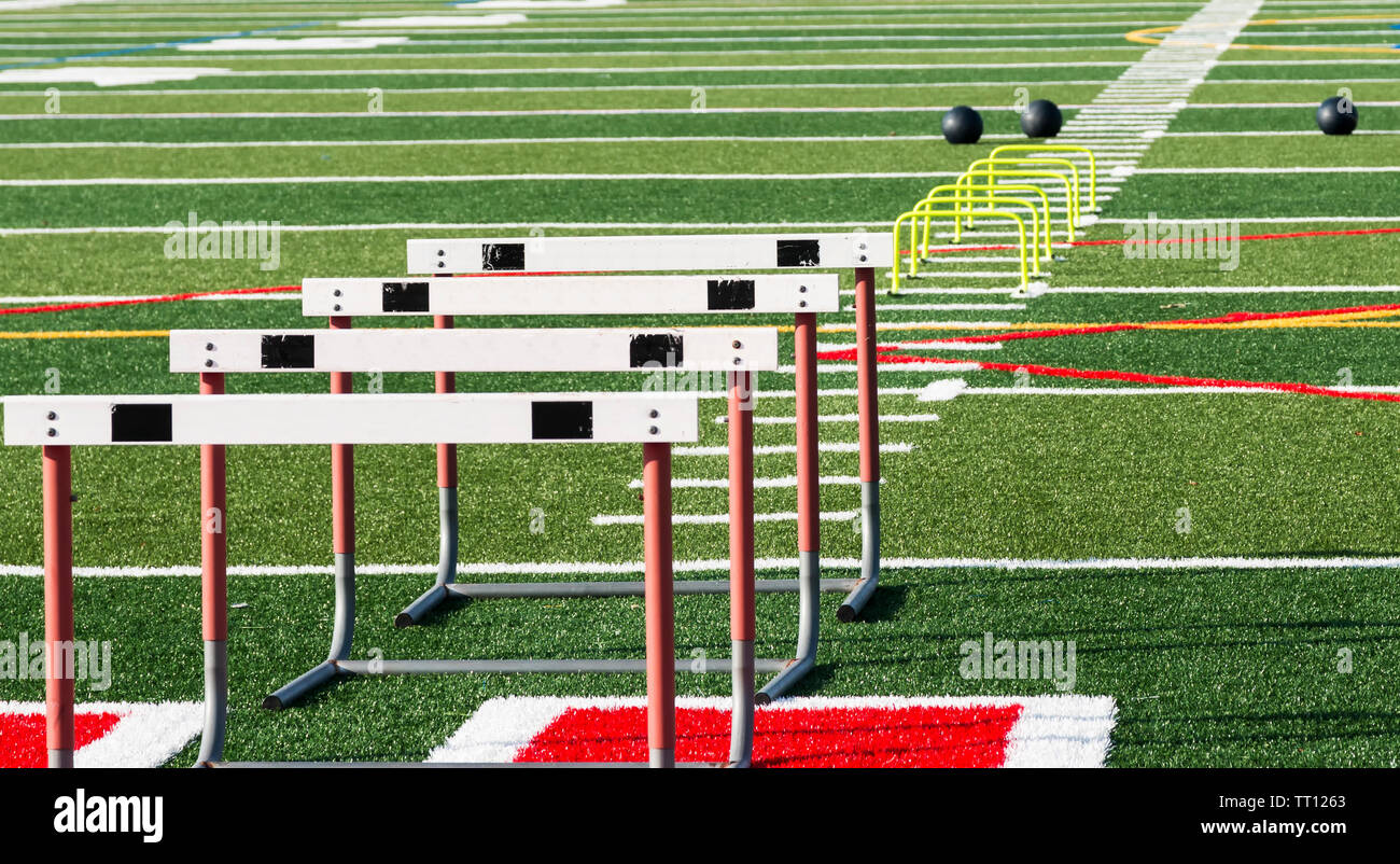 Hurdles and medicine balls are set up on a turf field for speed work training of high school ...
