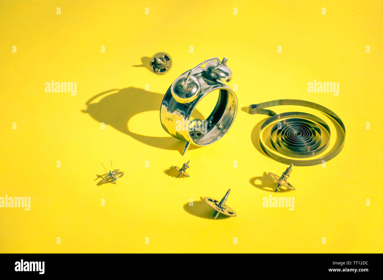 Old alarm clock disassembled into gears on a bright yellow background ...