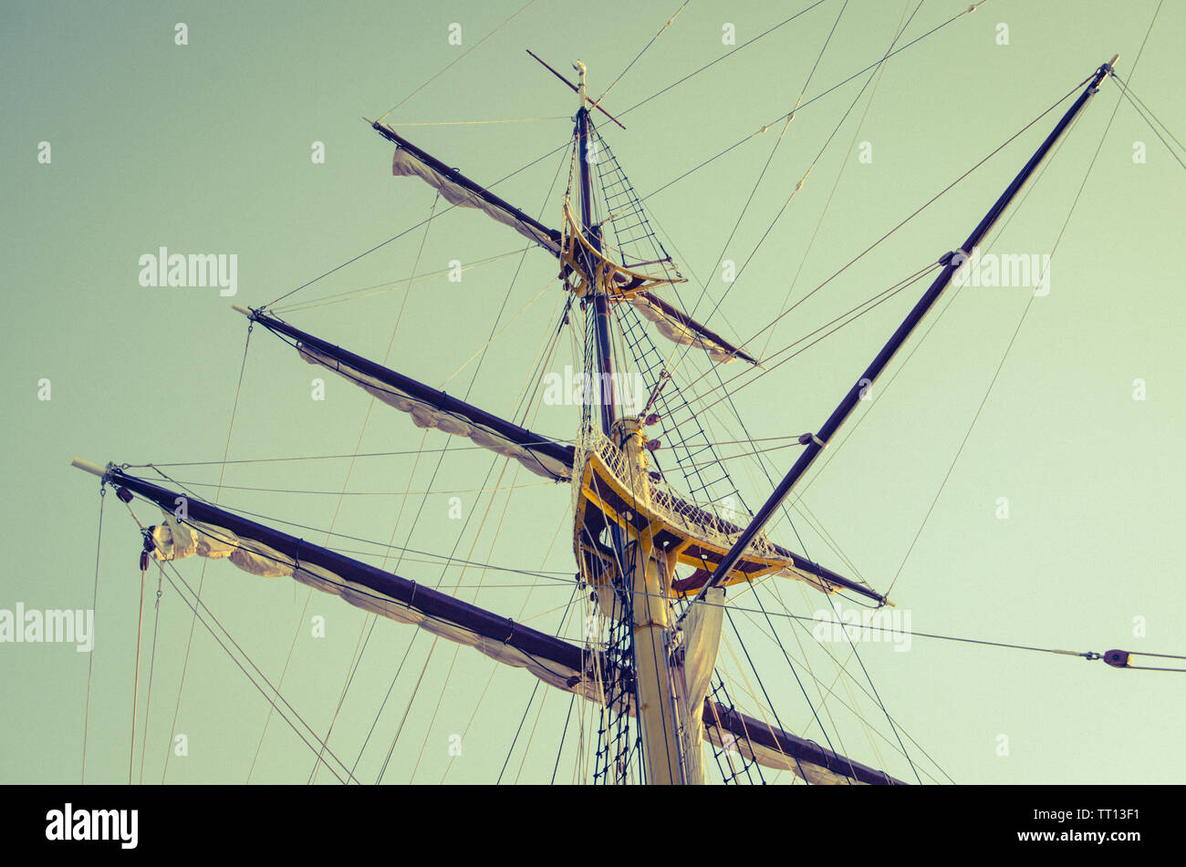 Mast sailing ship, with raised sails against the clear sky in calm ...