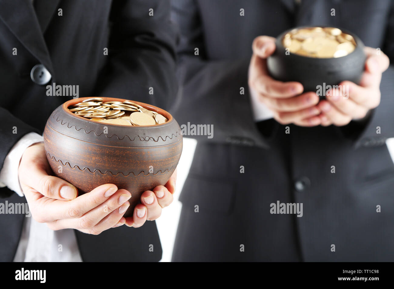 Two ceramic pots with golden coins in male and female hands, isolated ...