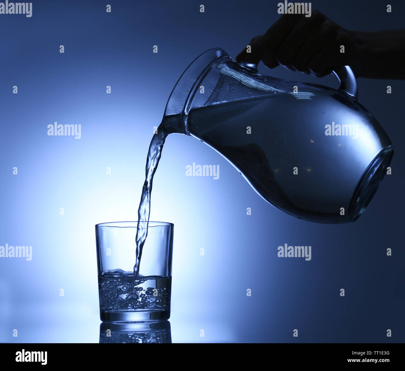 Pour water from pitcher into glass, on dark blue background Stock Photo ...